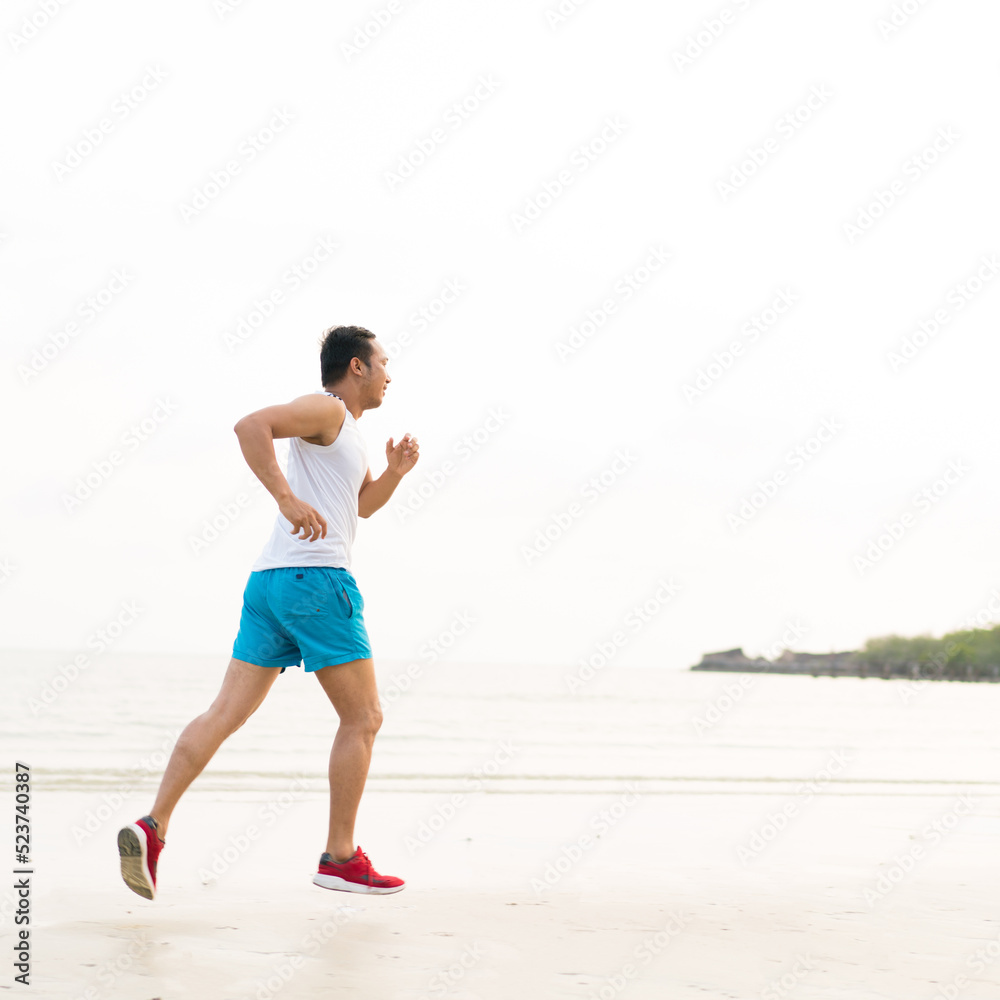 asian sport man running along seaside. running on beach with healthy ...