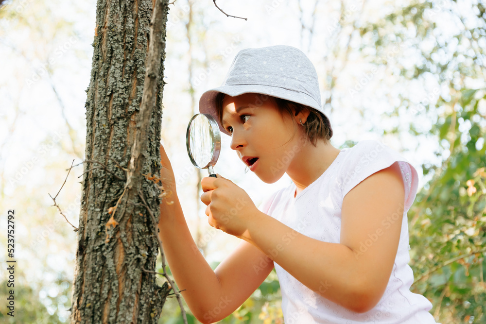 little child naturalist botanist with a magnifying glass is surprised ...