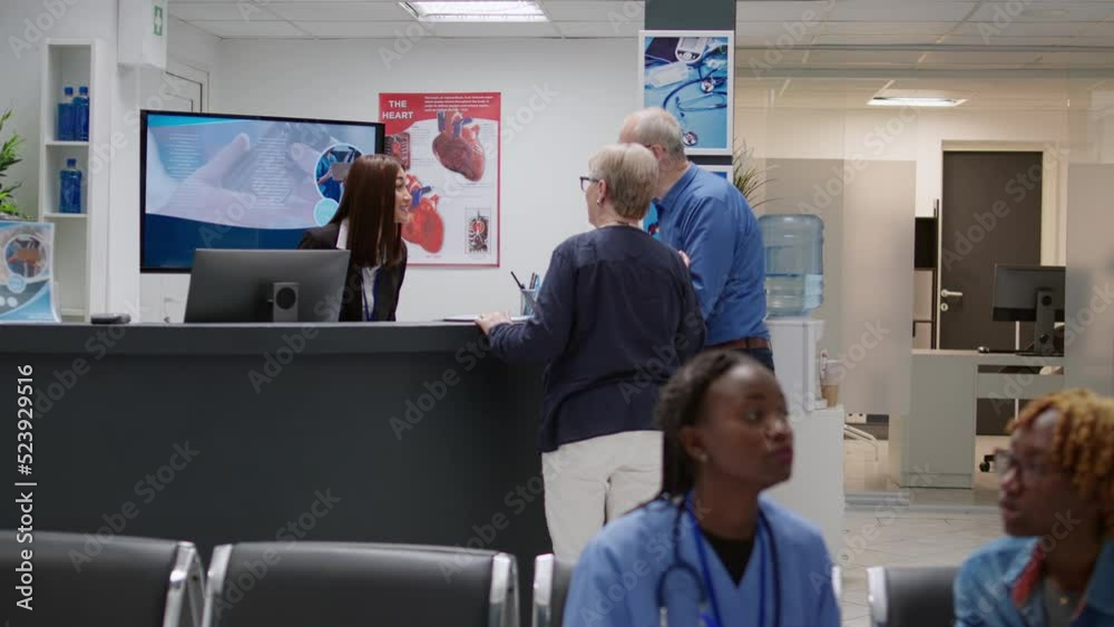 Retired people doing medical report with receptionist in hospital ...