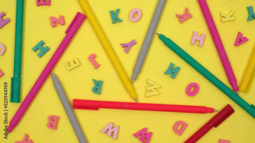 colored ballpoint pens and alphabet letters randomly lie on a rotating ...
