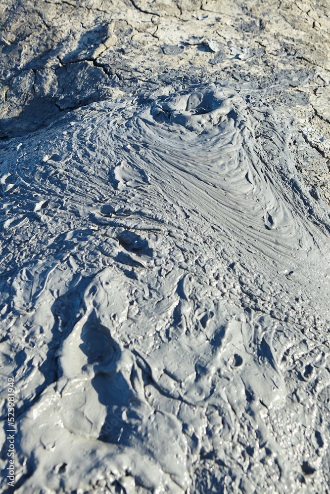 A mud volcano and a stream of grey clay from an eruption and gas escape ...