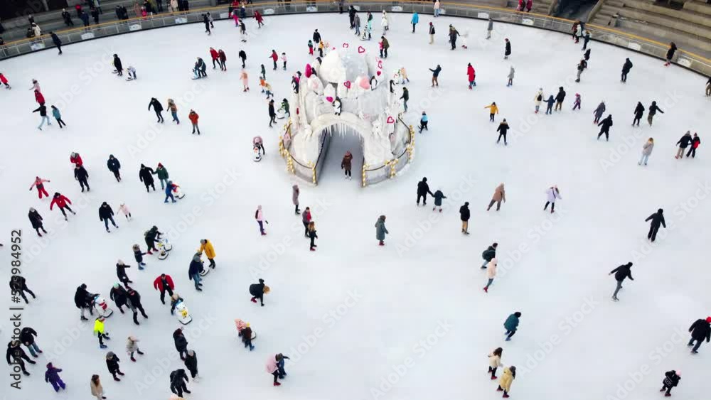 Many people are skating on a white outdoor ice rink in the city on ...