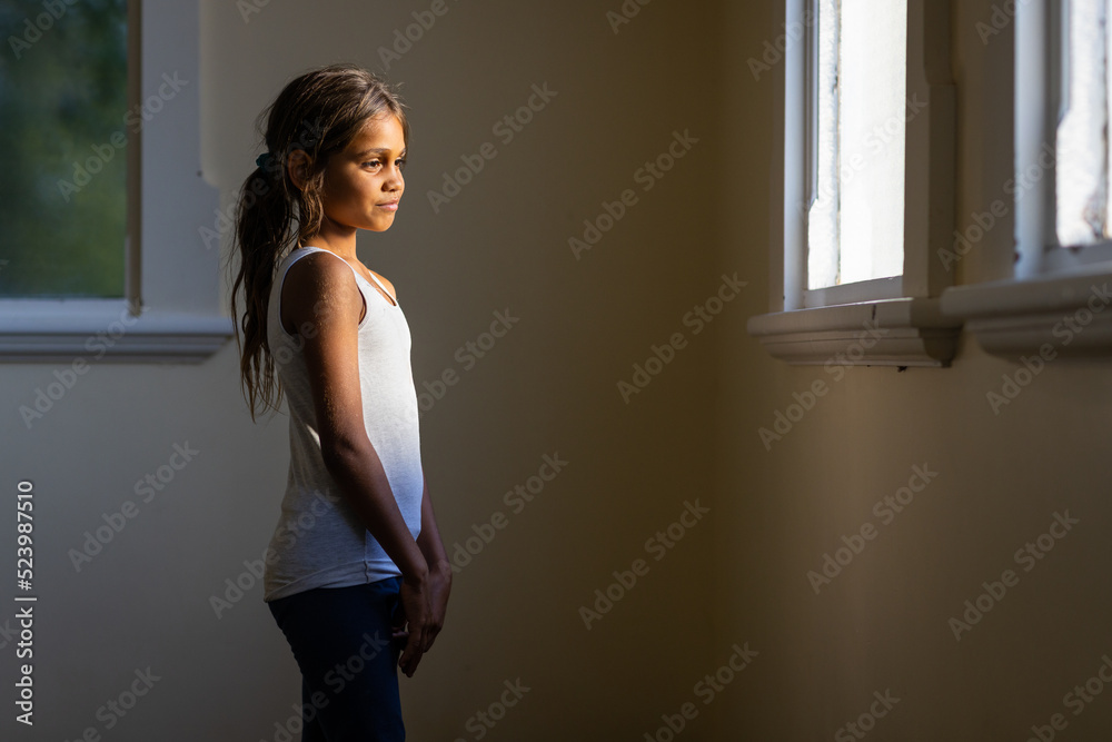 little girl in dingy room with light on her face looking towards bright ...