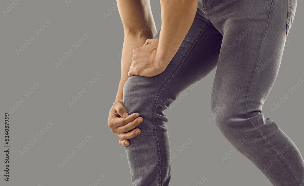 Close up crop of man on grey studio background have kneecap spasm ...