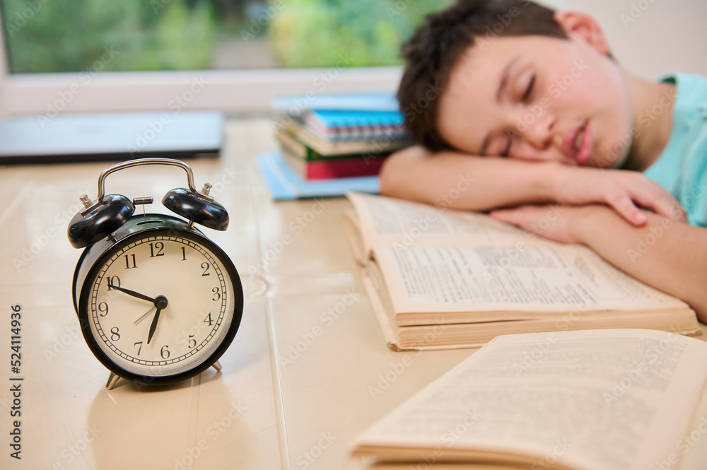 Focus on a black alarm clock on blurred background of a tired sleepy ...
