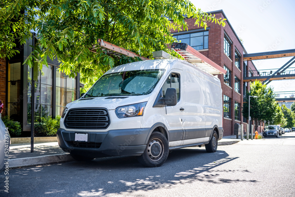 Commercial cargo mini van with ladder on the roof standing on the urban ...