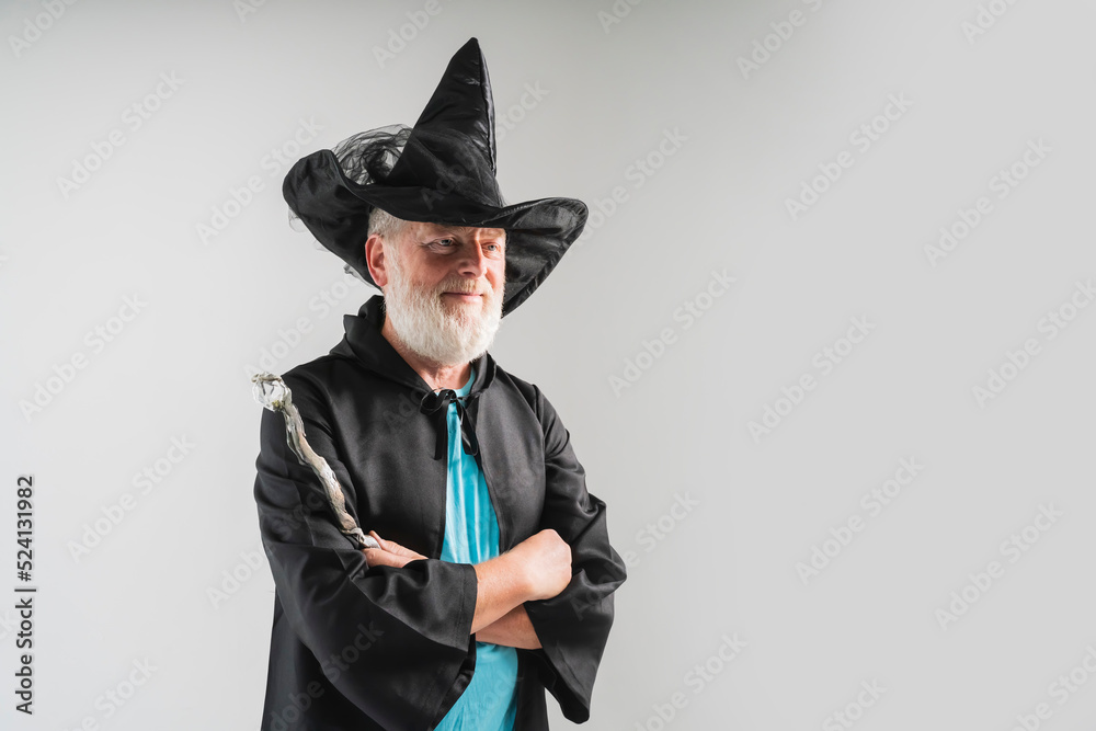 old wizard man shows magic wand in a Halloween costume, on a white ...