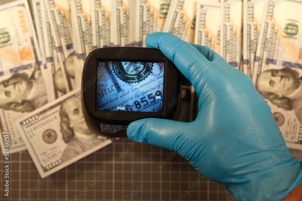 Checking the authenticity of dollars with a currency detector close-up ...
