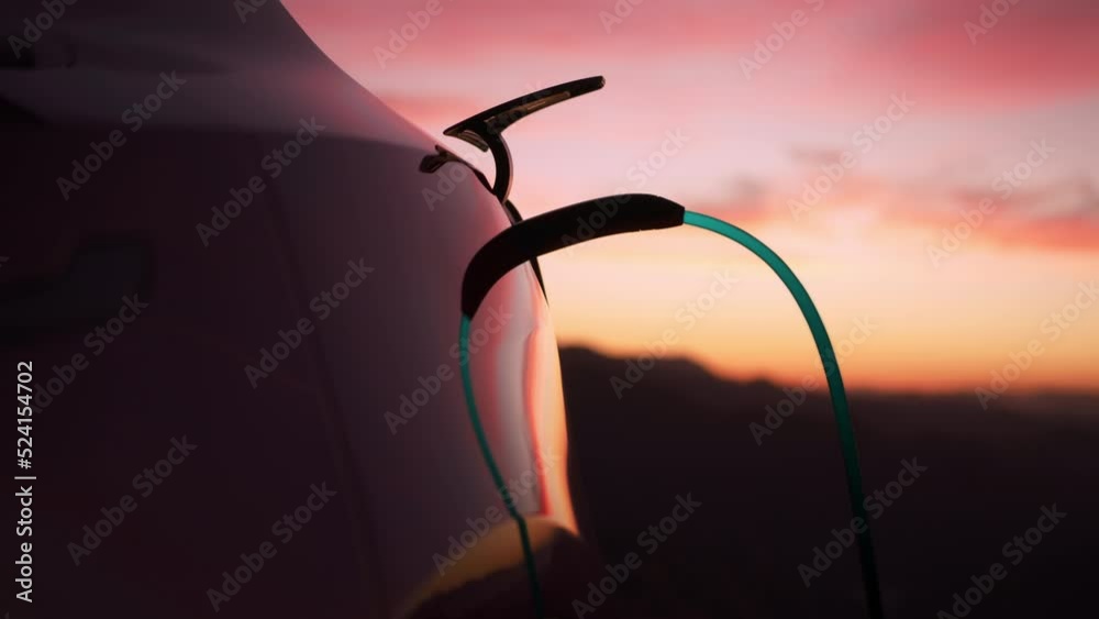 Close up of generic electric car charging with cinematic pink sunset on ...