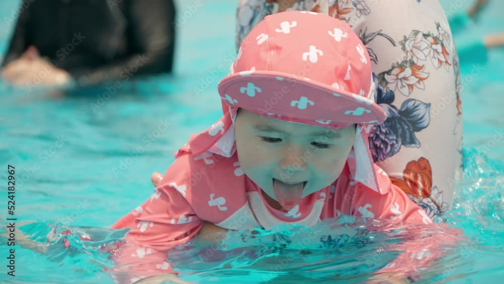 Mother embraces the offspring girl in the outdoor swimming pool trying ...