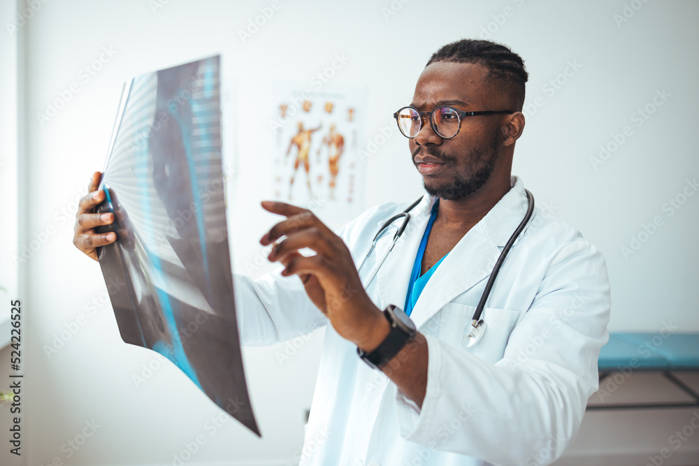 Male radiologist analyzing chest X-ray of an patient at medical clinic ...