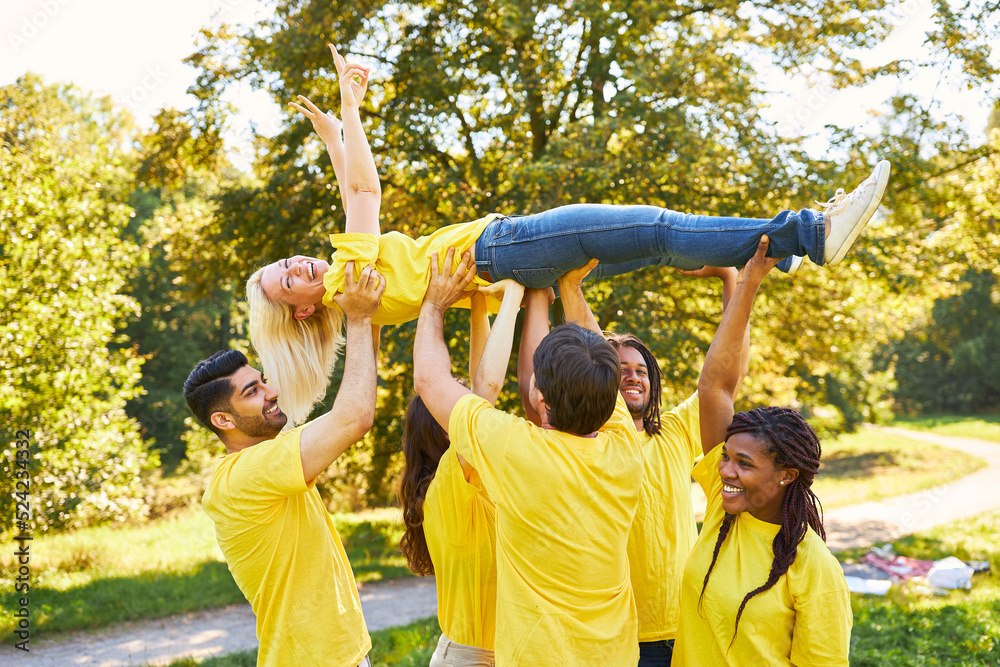 Gruppe junger Leute hebt gemeinsam Frau hoch Stock Photo | Adobe Stock