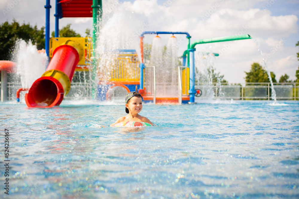Happy laughing child in the pool at the water park. Cute boy in bright ...