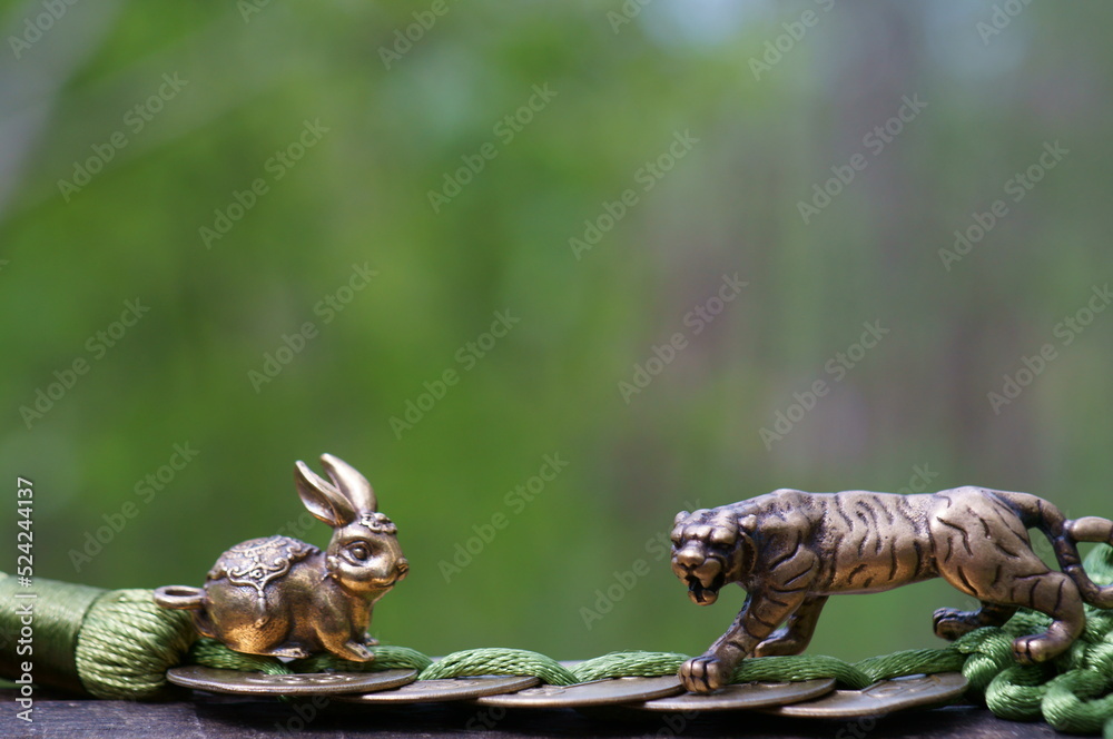 Metal rabbit and tiger figurine with Chinese coins. An esoteric symbol ...