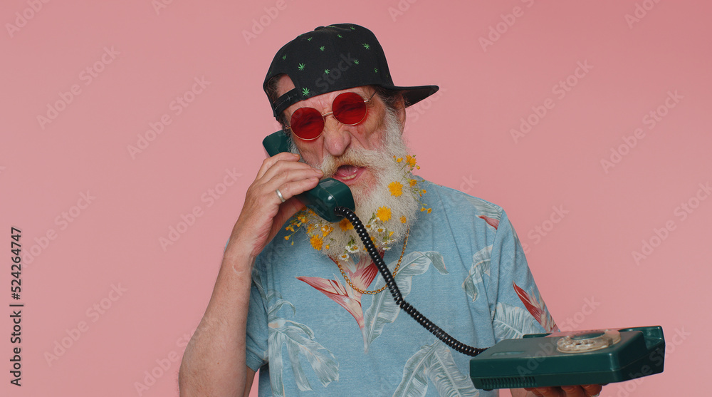 Crazy stylish senior man with flowers in gray-haired beard talking on ...