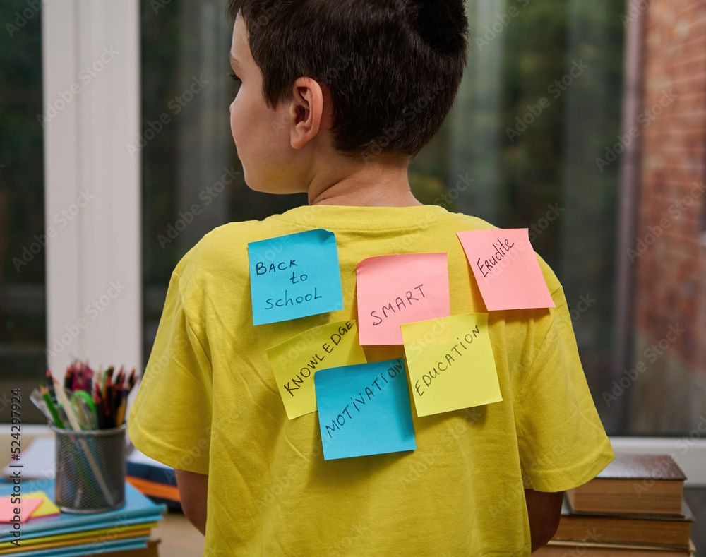Rear view of a multitasking primary school student with colored paper ...