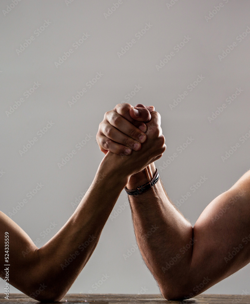 Two man's hands clasped arm wrestling, strong and weak, unequal match ...