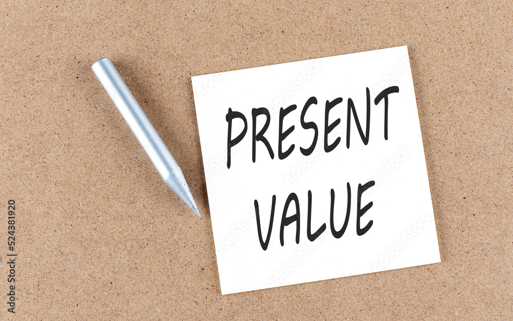 PRESENT VALUE text on a sticky note on cork board with pencil Stock ...