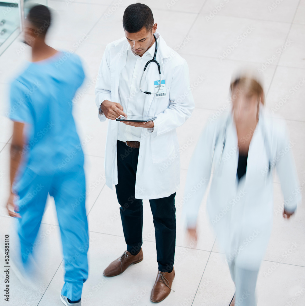 Busy hospital with doctor browsing on tablet for test results, patient ...
