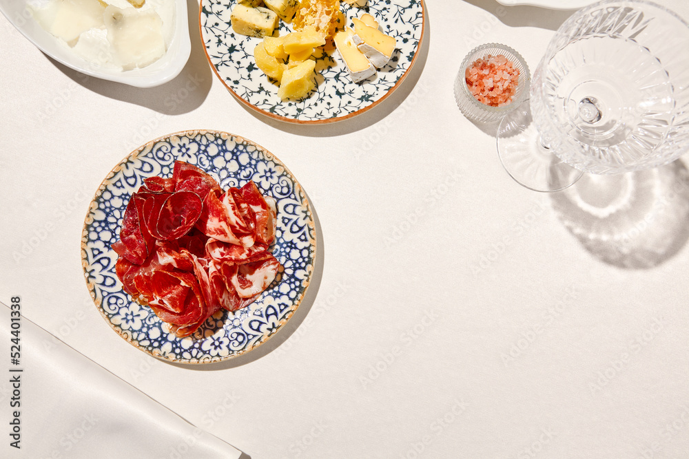 Meat antipasti on ceramic plate on white table with hard shadow. Meat ...