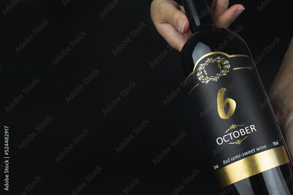 October 6th. Day 6 of month, Calendar date. Hands hold bottle of red ...