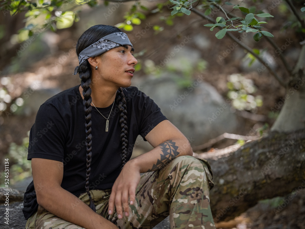 Indigenous man sitting and relacing while looking to his left in a ...