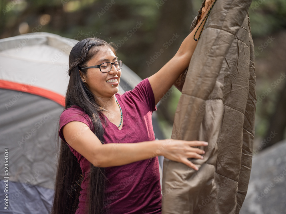 Indigenous woman smiling while unrolling her sleeping bag in the ...