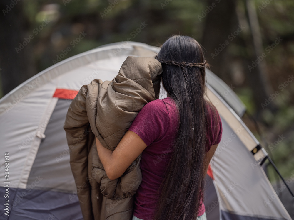 Horizontal back view image of an Indigenous woman putting a sleeping ...