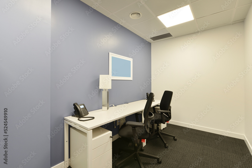 Poster Small office cubicle with a white table, two chests of drawers ...