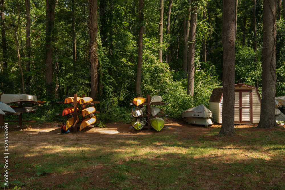racks of small water craft; kayaks, canoes and a small wooden shed in a ...