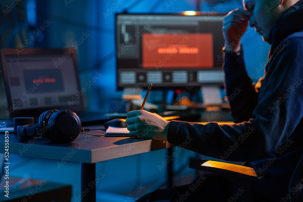 cybercrime, hacking and technology concept - close up of male hacker in dark room writing to ...