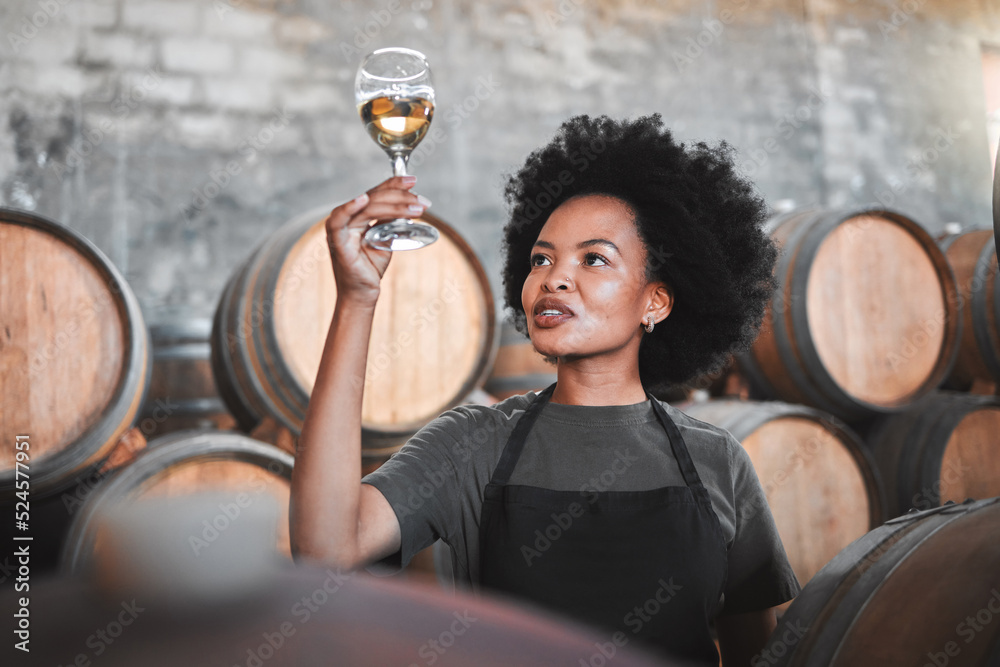 Black woman tasting wine at a winery, looking and checking the color ...