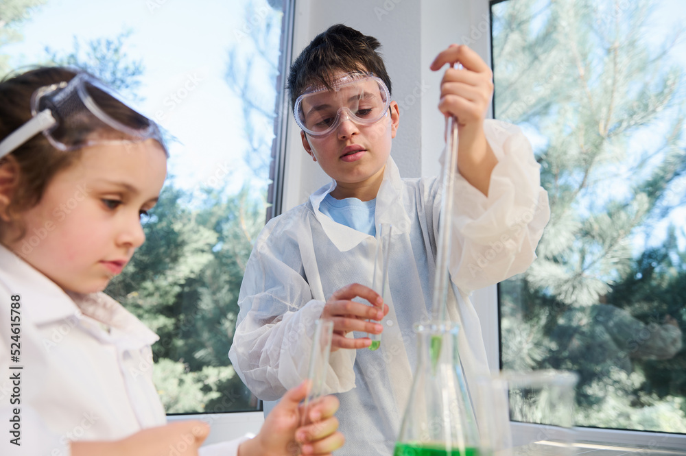 Schoolboy using pipette, dripping few reagents in the flask with ...