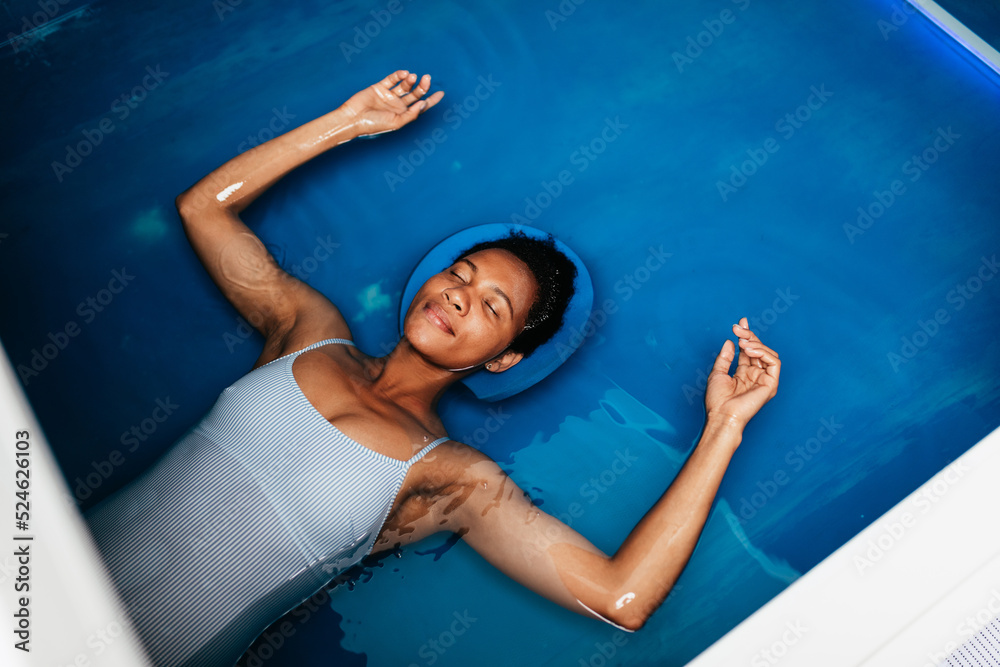 Beautiful middle-aged African American woman floating in tank filled ...