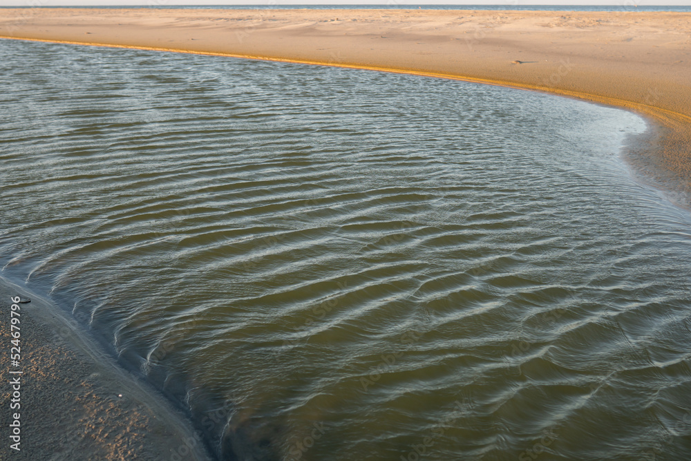thin pool of sea water trapped on a sand bar after the outgoing low ...