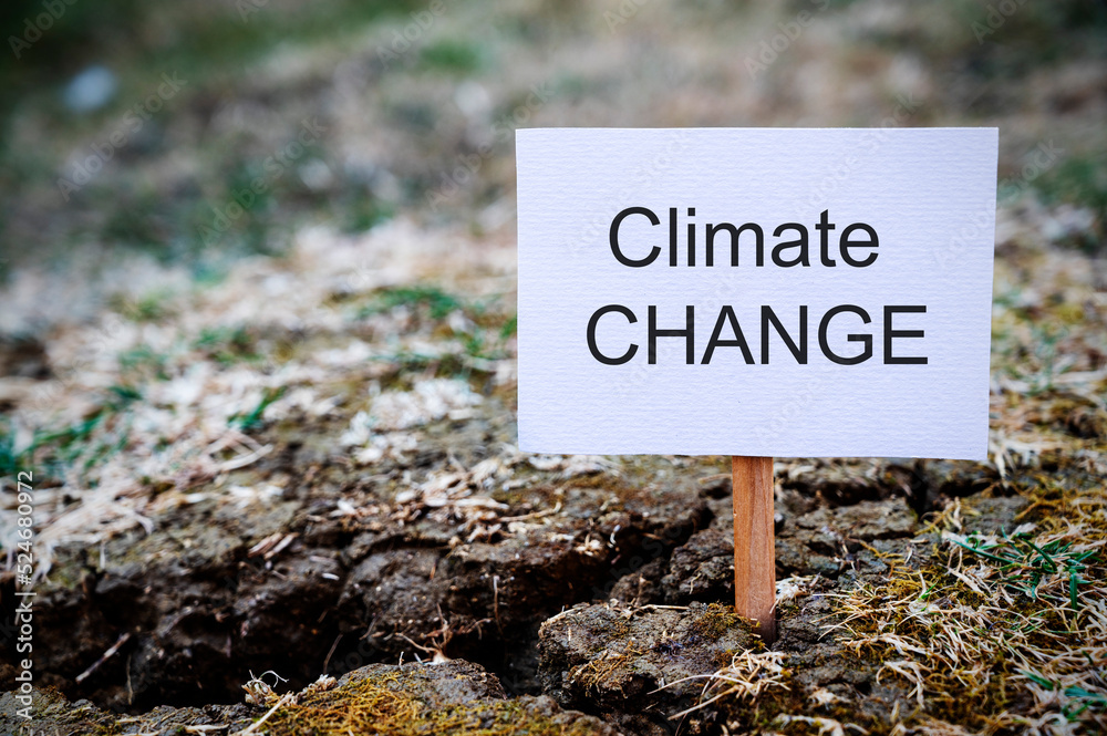 Climate change words written on white paper, over dry soil with dried ...