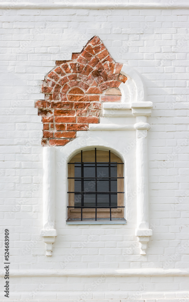 Figured arched barred window in ancient white brick wall. Medieval ...