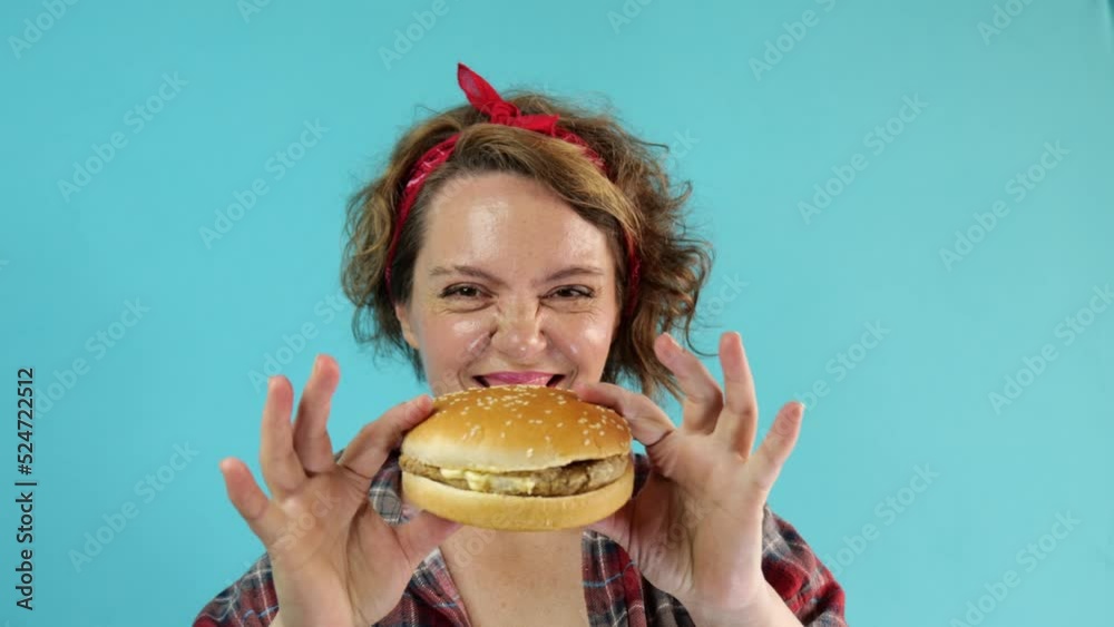 Vidéo Stock Adult pin-up woman in a plaid shirt eats a burger on an ...