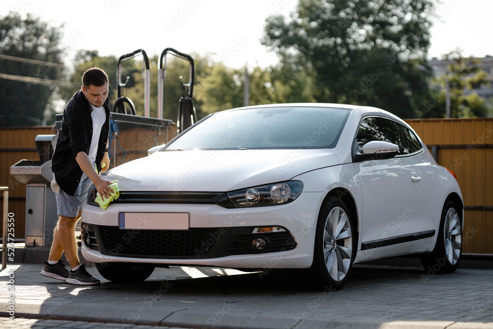 Man is wiping the car with a microfiber cloth. Contactless self-service ...
