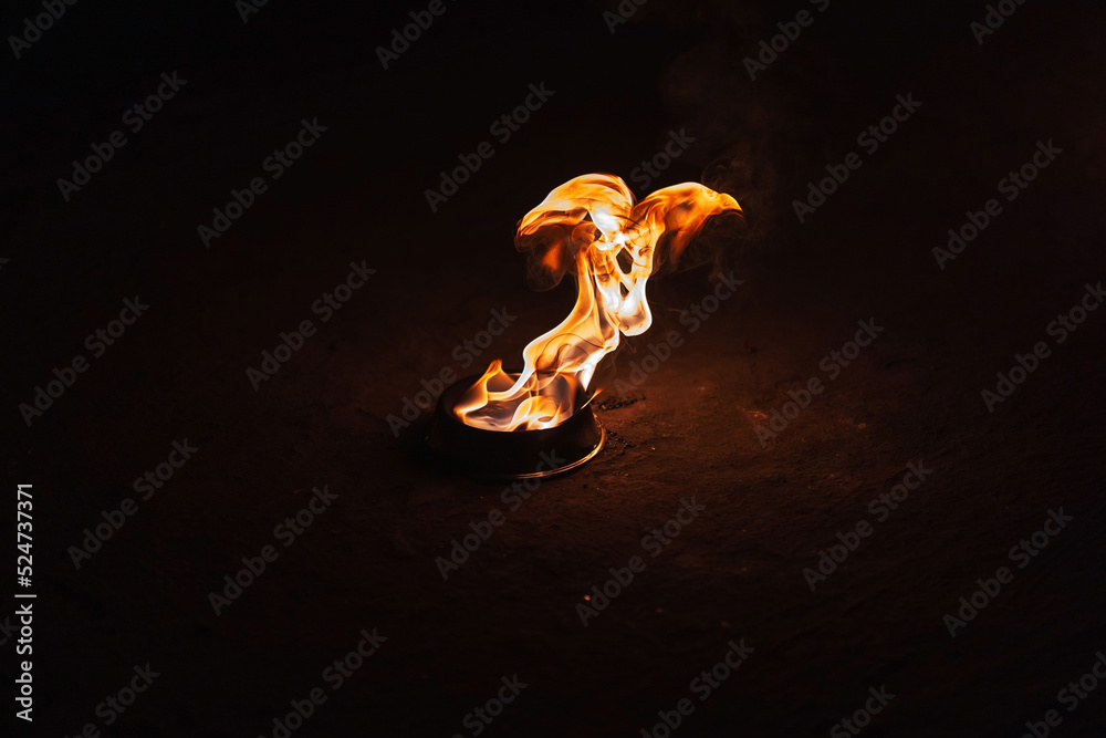 orange fire on a dark background. Burning kerosene in an iron plate. a ...