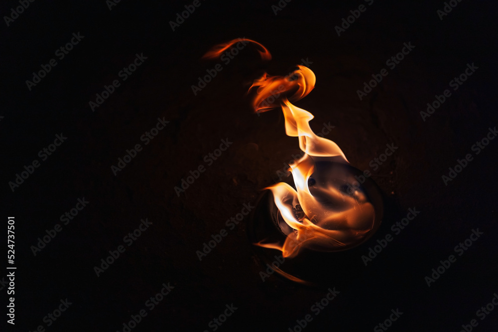 orange fire on a dark background. Burning kerosene in an iron plate. a ...