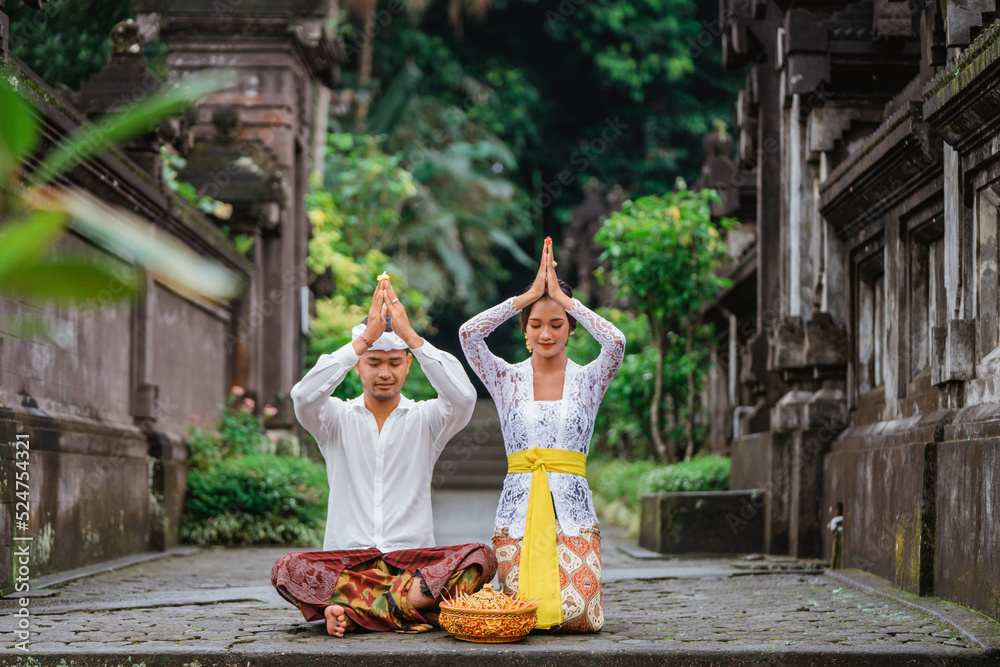 balinese couple do the prayer to god in the morning. hindu people make ...