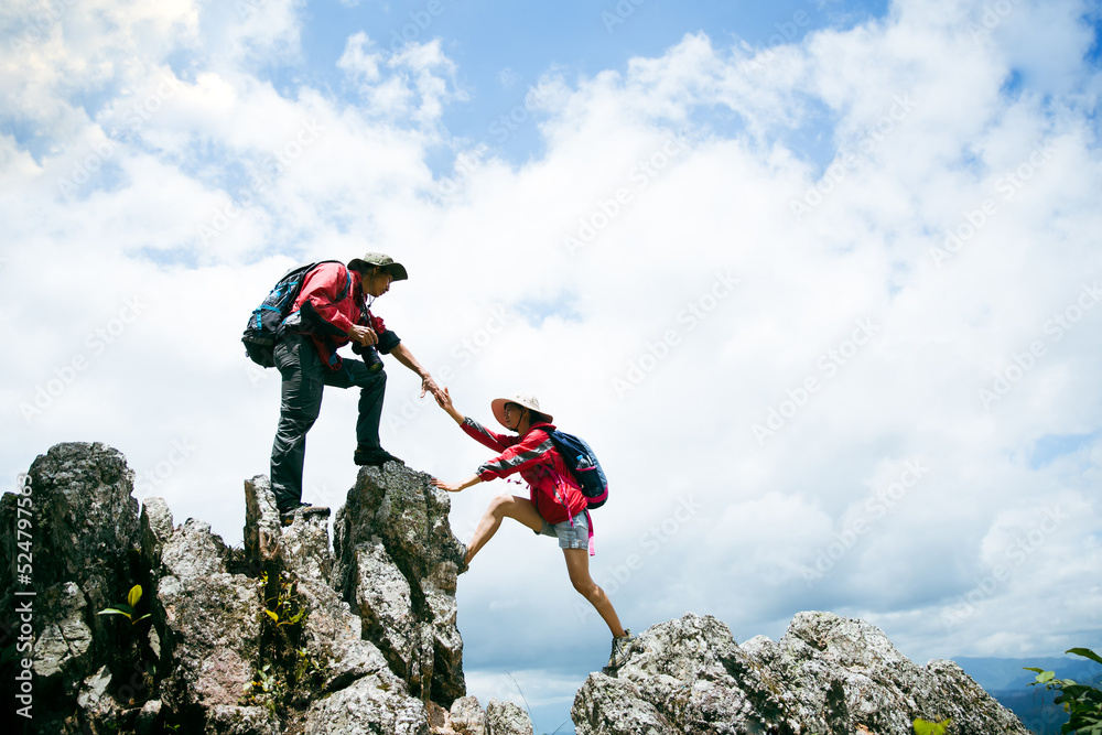 Person hike friends helping each other up a mountain. Man and woman ...
