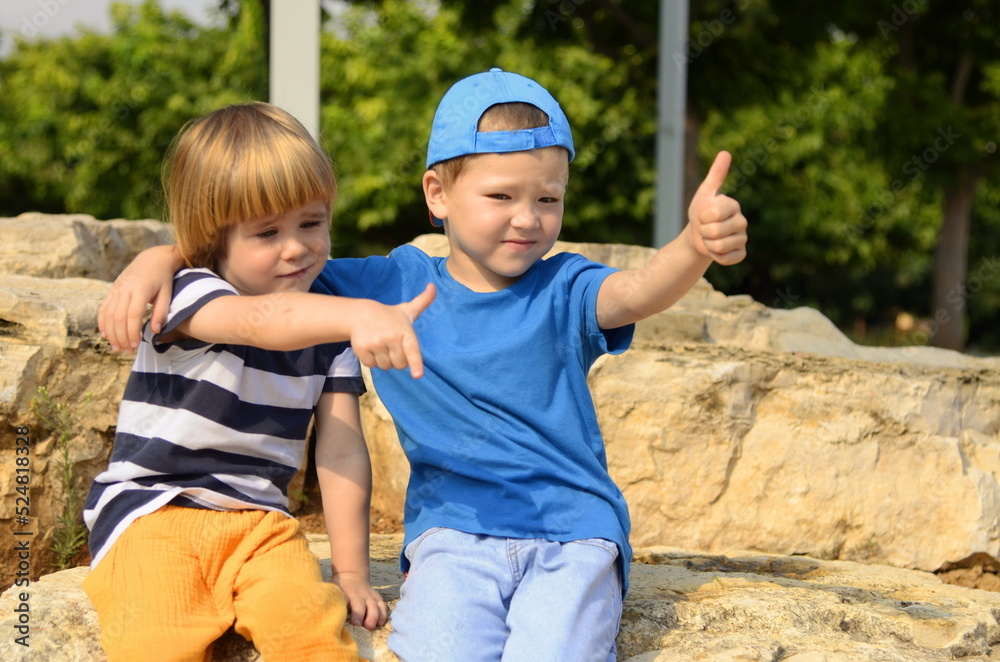 Two little boys, two friends, brothers are sitting on the street ...
