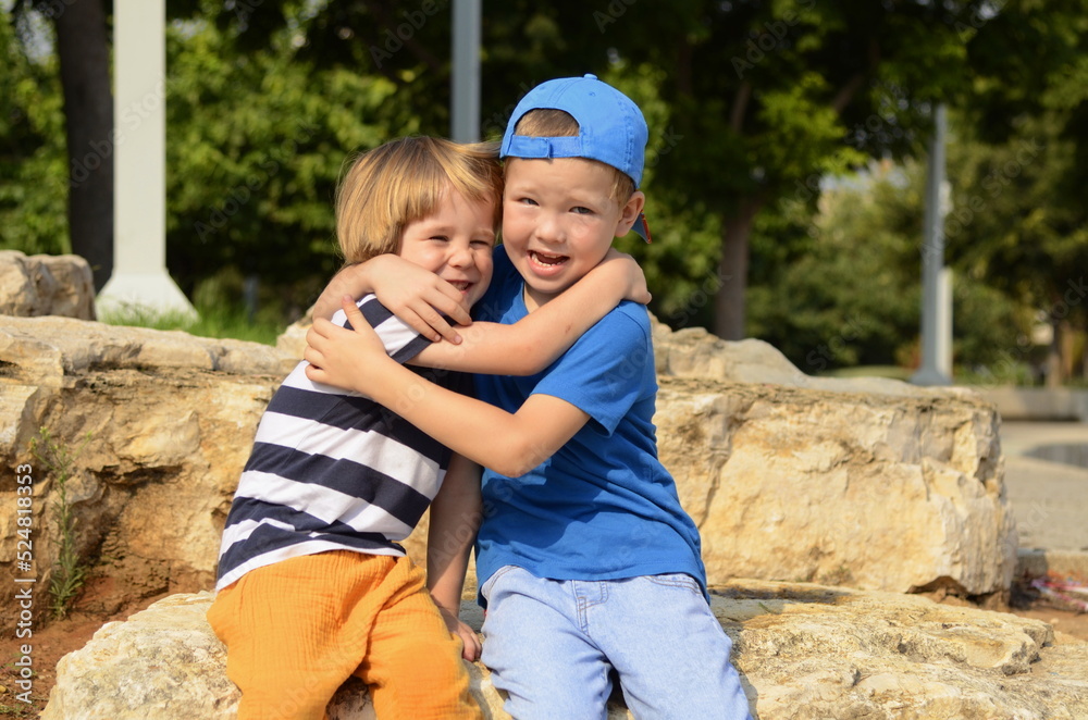 Two little boys, two friends, brothers are sitting on the street ...