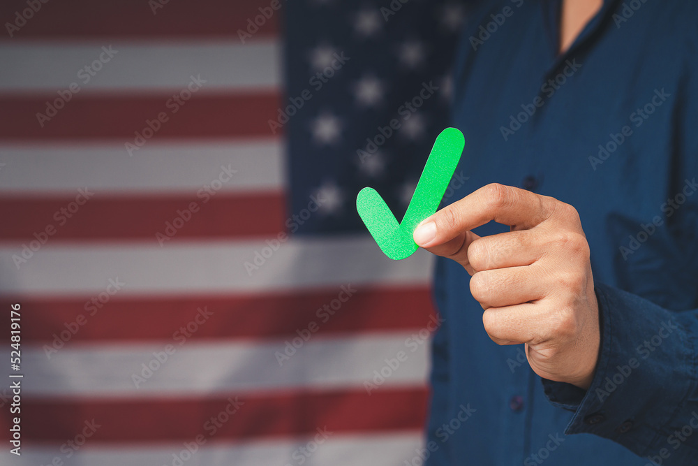 Hand holding a green check mark symbol while standing on the American ...