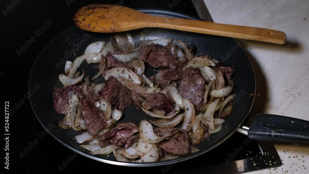 Chopped, half-ready white onion and bloody liver pieces frying in a hot ...