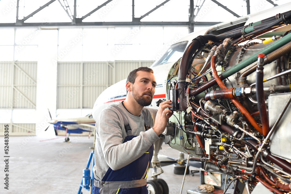 Aircraft mechanic repairs an aircraft engine in an airport hangar Stock ...