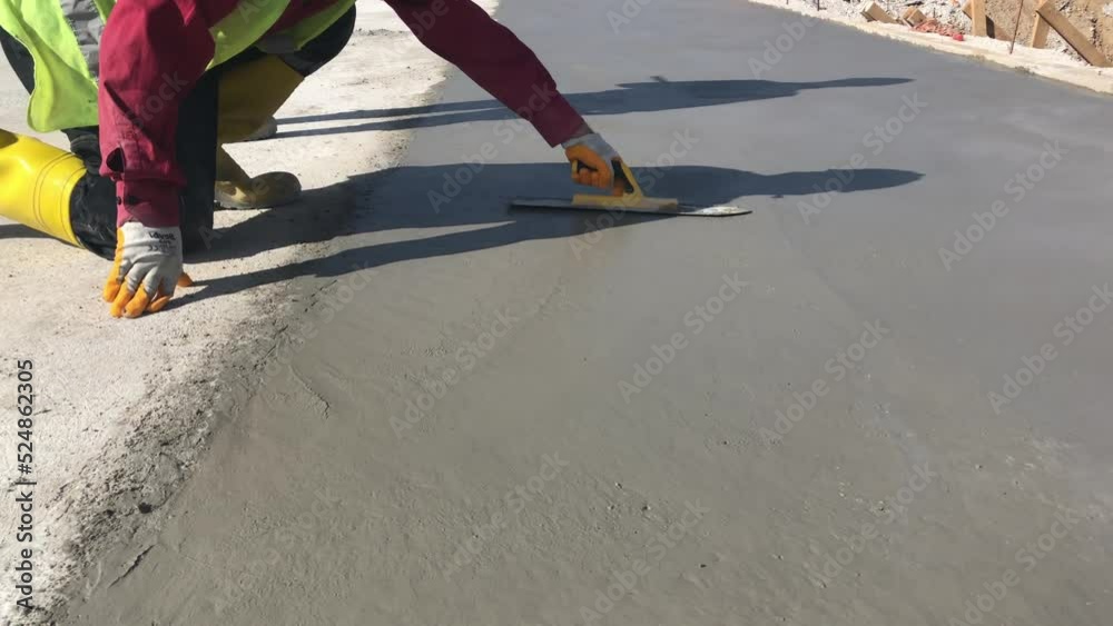 Construction worker uses trowel to level cement mortar screed. Concrete ...