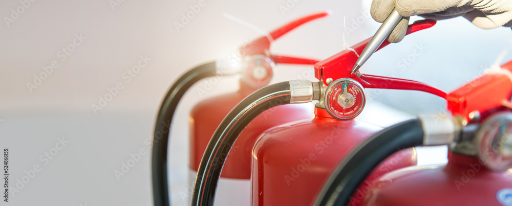 Close up fire extinguisher and firefighter checking pressure gauge ...